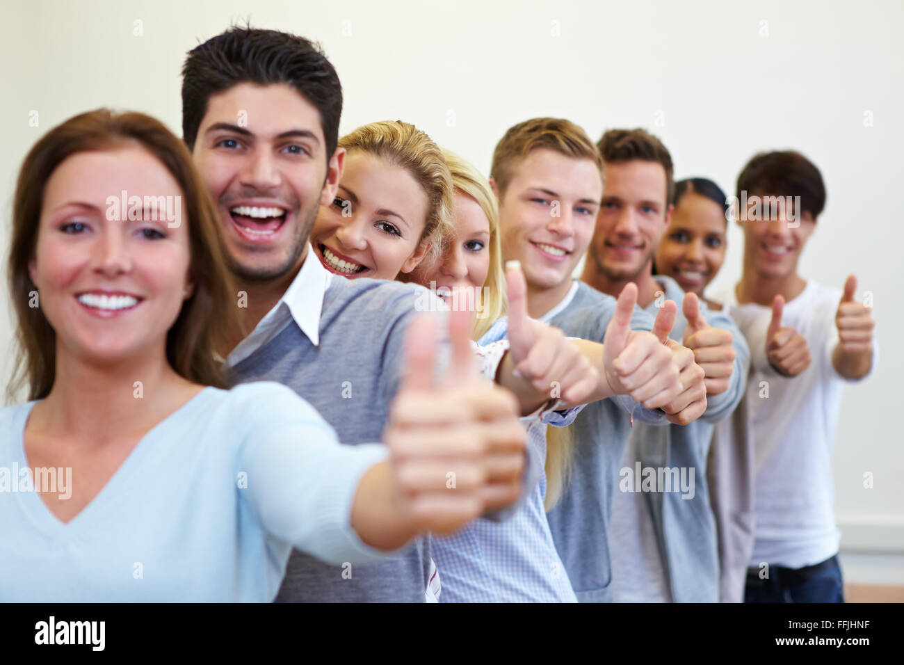 Happy smiling students in a row with their thumbs up Stock Photo - Alamy