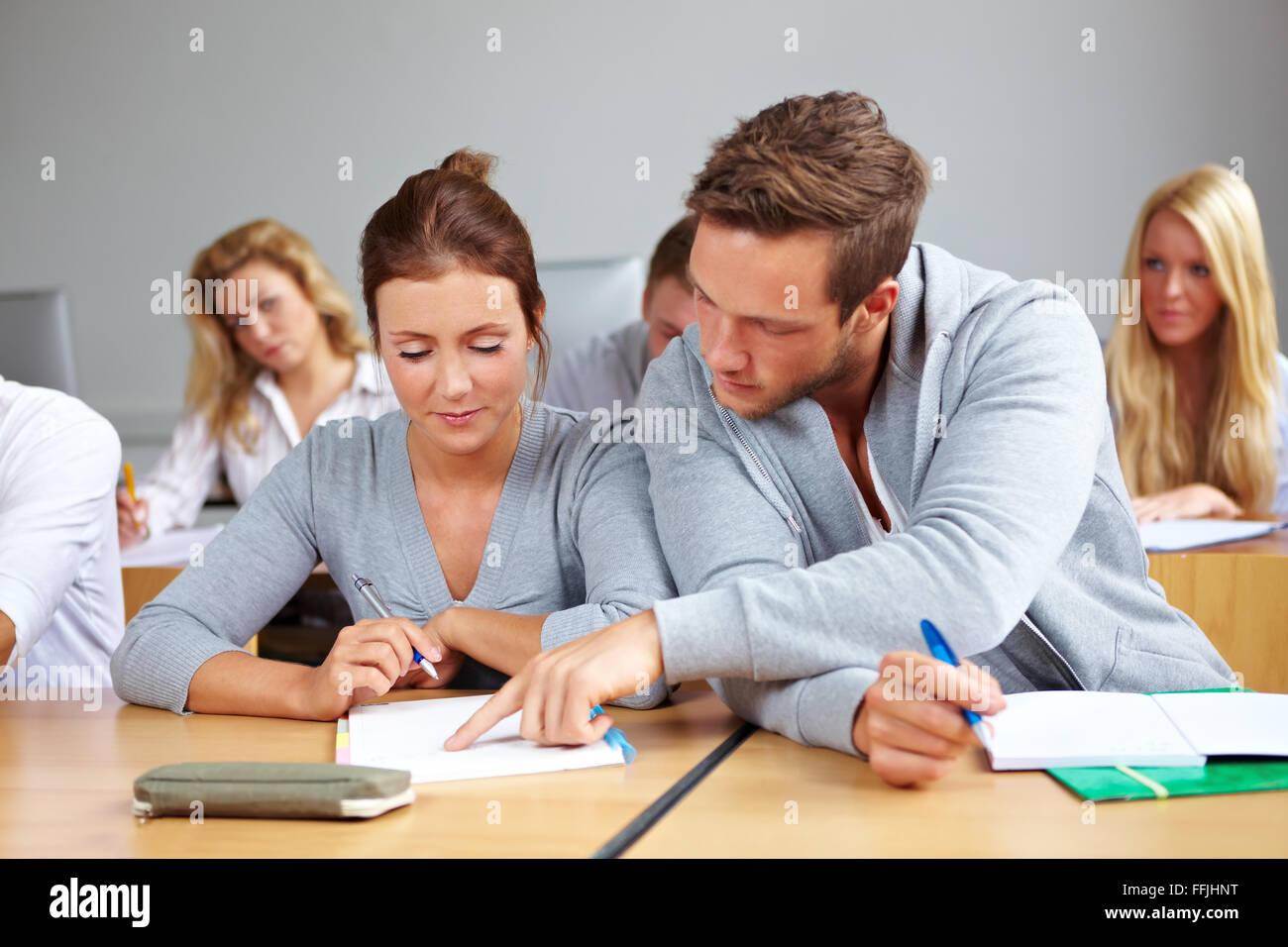 Student helping other student in class in university Stock Photo - Alamy