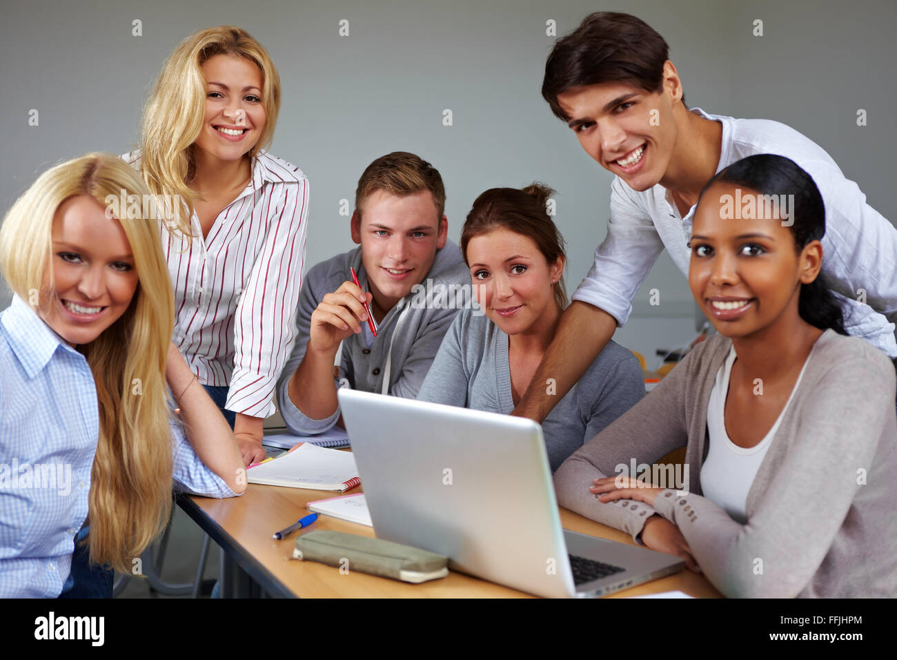 Portrait of group of students around laptop Stock Photo - Alamy