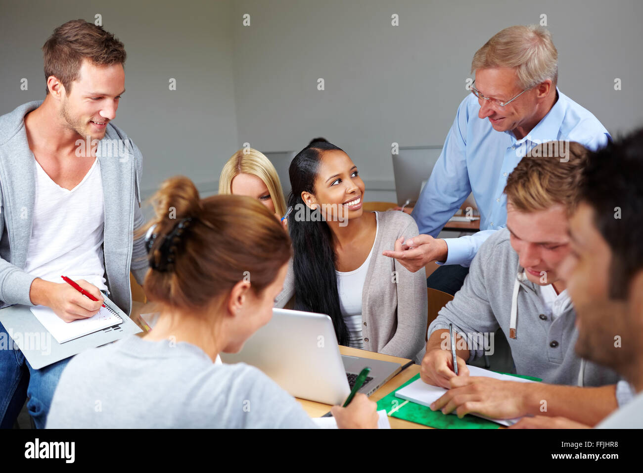 Teacher helping college students in study class Stock Photo - Alamy