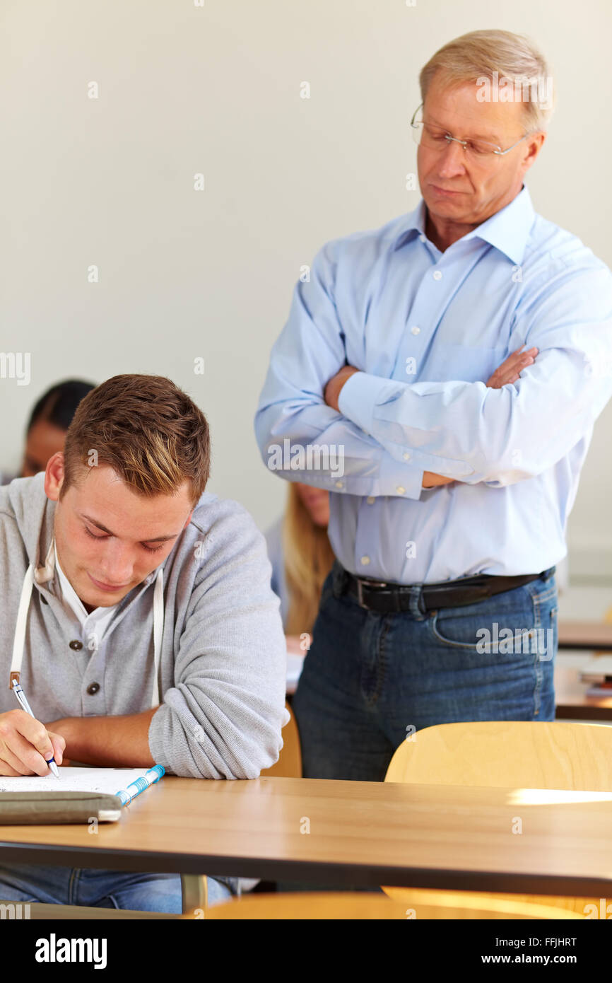 Teacher checking students at test in university Stock Photo - Alamy