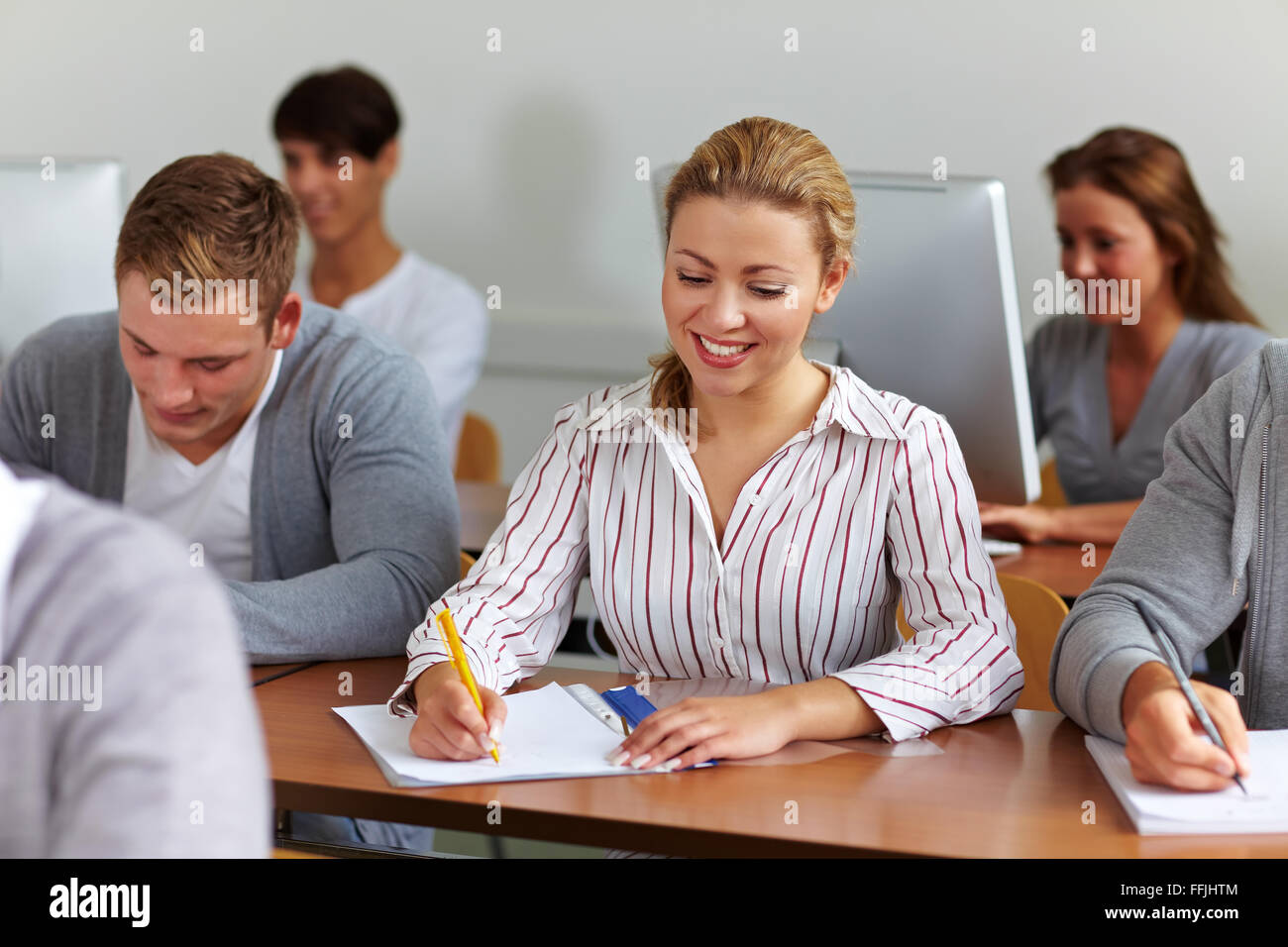 Happy female student taking notes in university class Stock Photo - Alamy