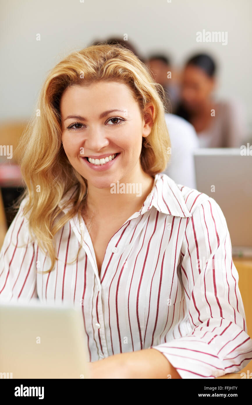 Smiling female student at laptop in university class Stock Photo - Alamy
