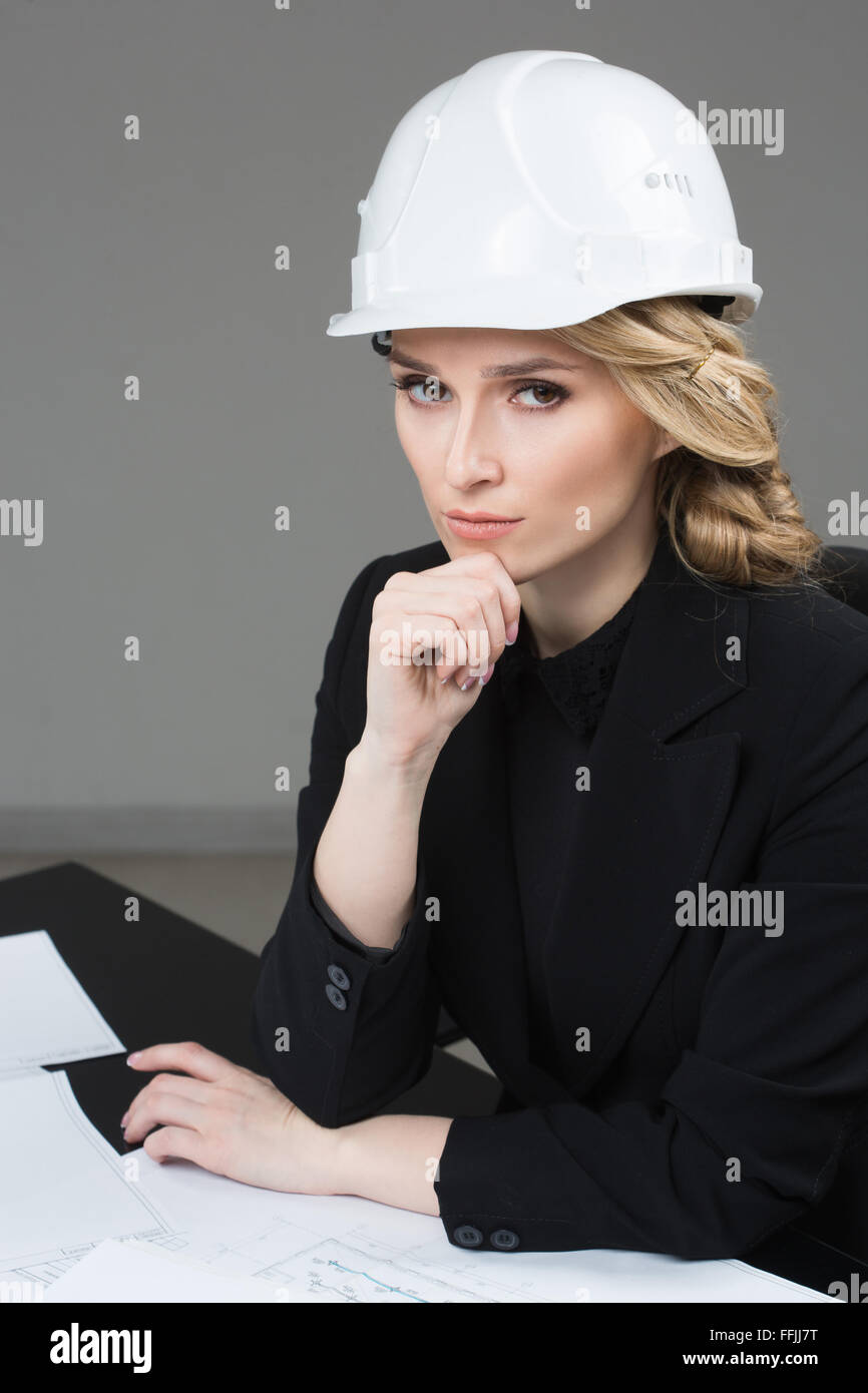 Woman architect with drawings. Beautiful girl in a building helmet ...