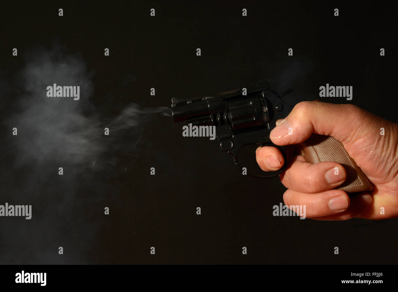 Small revolver smoking after firing. Held in male hand. (Toy Gun Stock ...