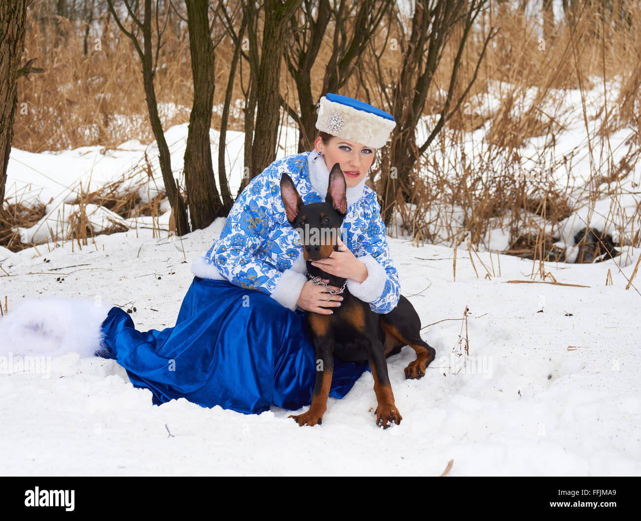 Young russian woman in traditional winter clothing with Doberman ...