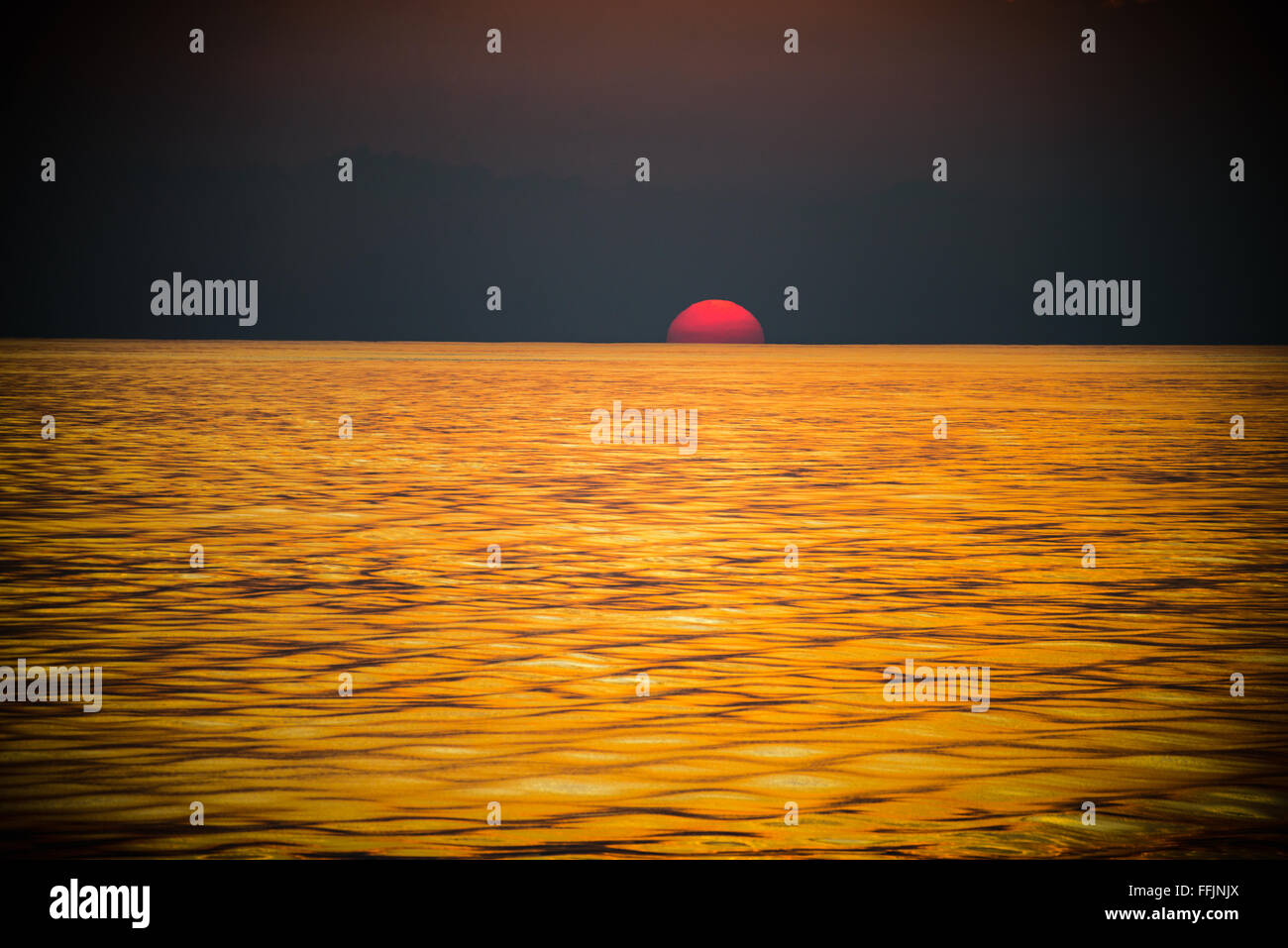 A beautiful red sun setting in the Indian ocean Stock Photo - Alamy