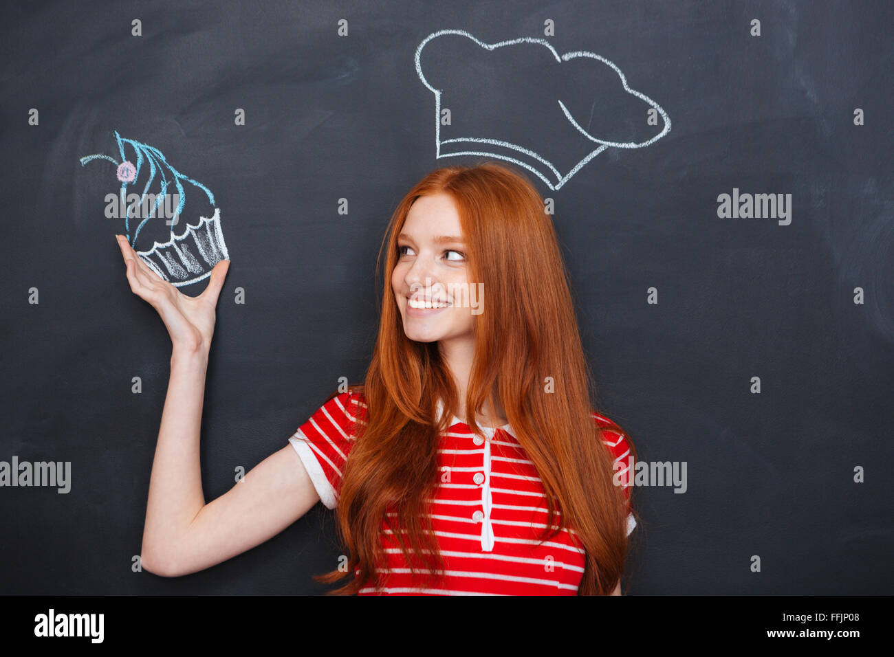Charming happy redhead young woman in drawn chef hat holding drawing ...