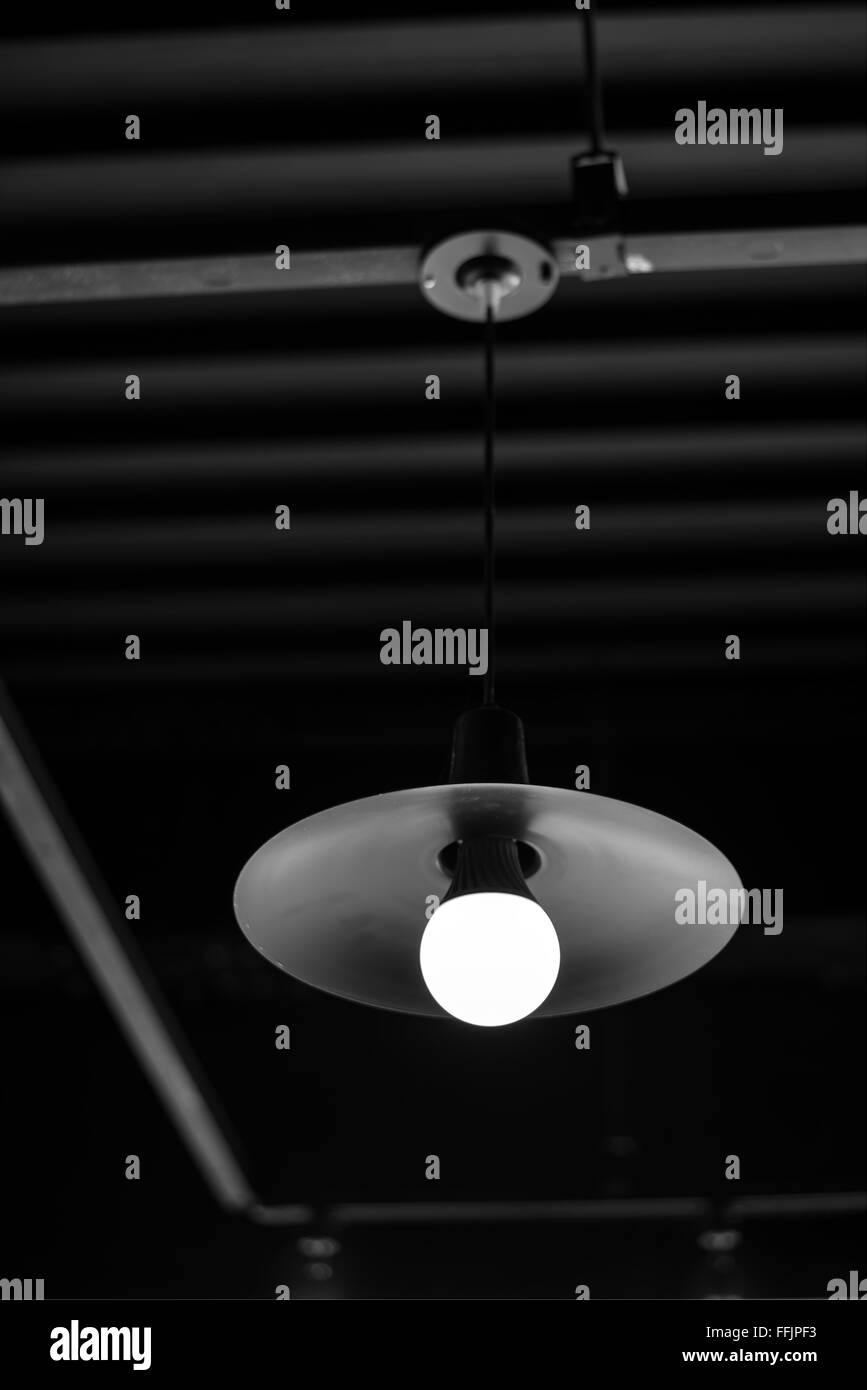 Light bulb turned on over black background. A black and white photo ...