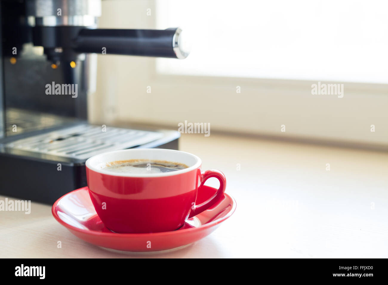 Red cup of coffee with coffee machine behind. Brewing morning coffee or ...