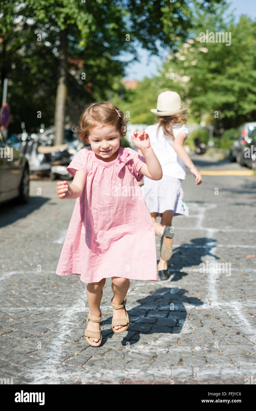 Two girls playing hopscotch on cobblestone Stock Photo - Alamy