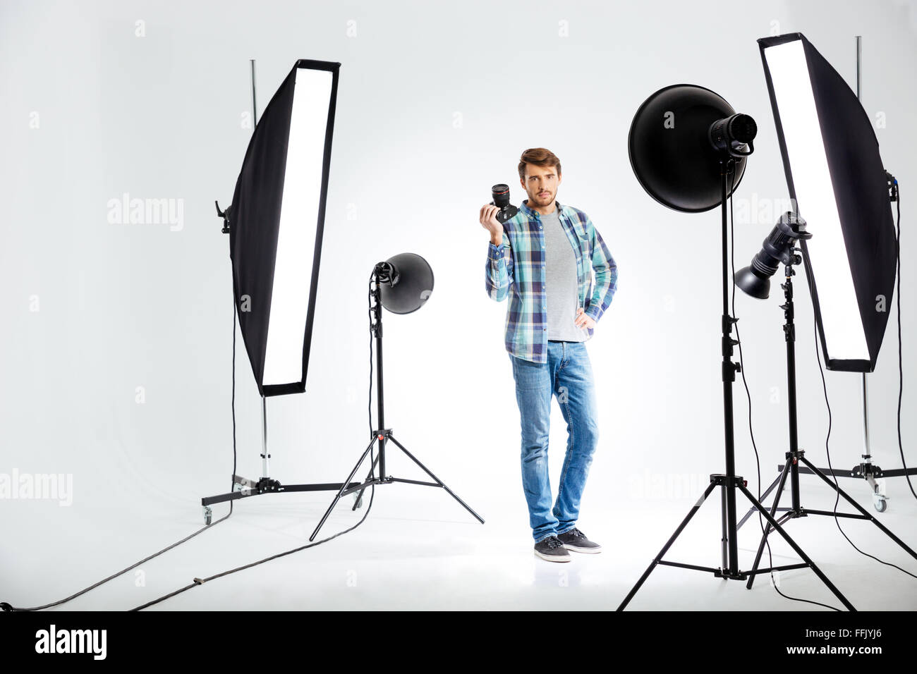 Full length portrait of a young photographer standing with photo camera ...