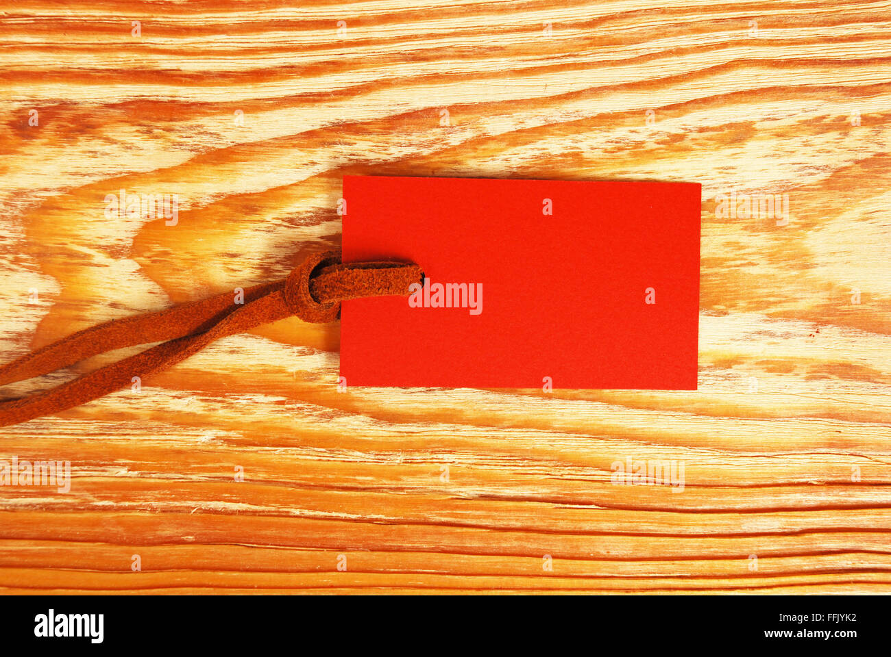 The red tag on brown leather rope on the background of wood Stock Photo ...