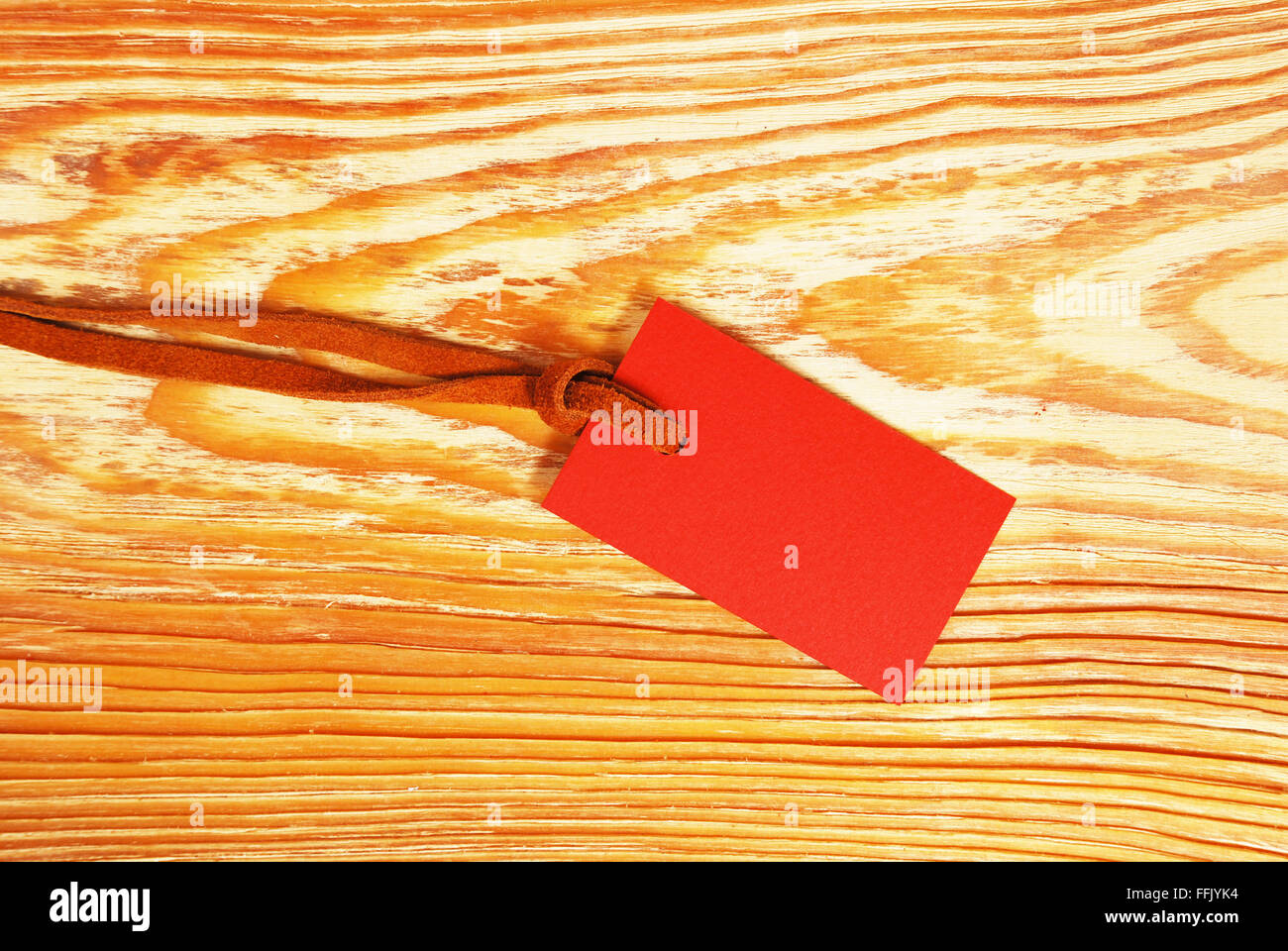 The red tag on brown leather rope on the background of wood Stock Photo ...