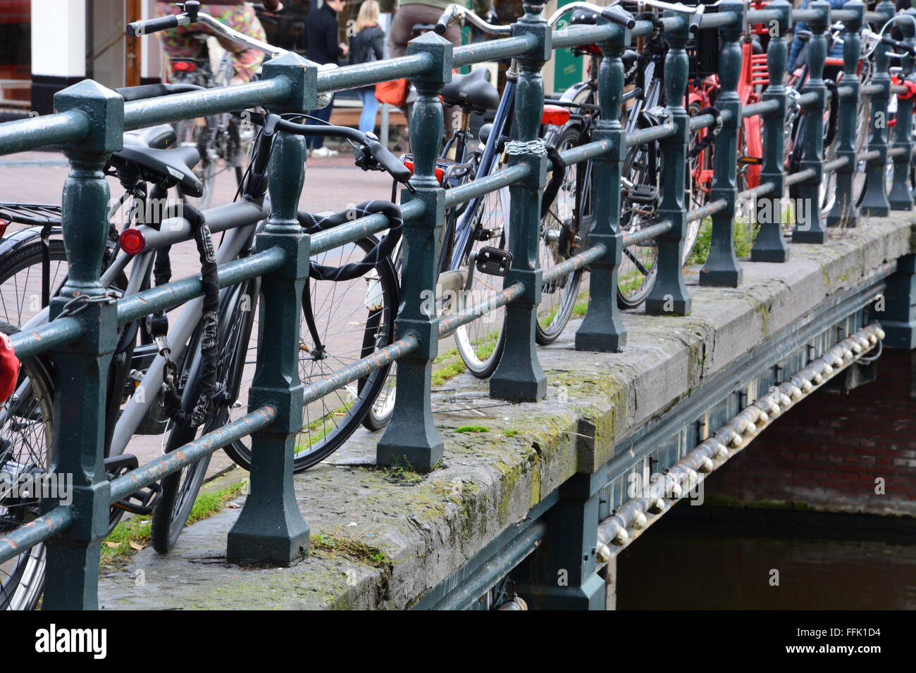 Close up of bicycles are locked to the railing of a bridge over the ...