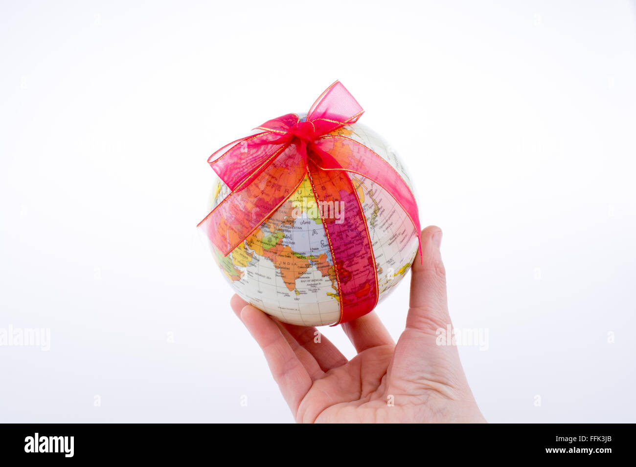 Globe tied with red ribbon on a white background Stock Photo - Alamy