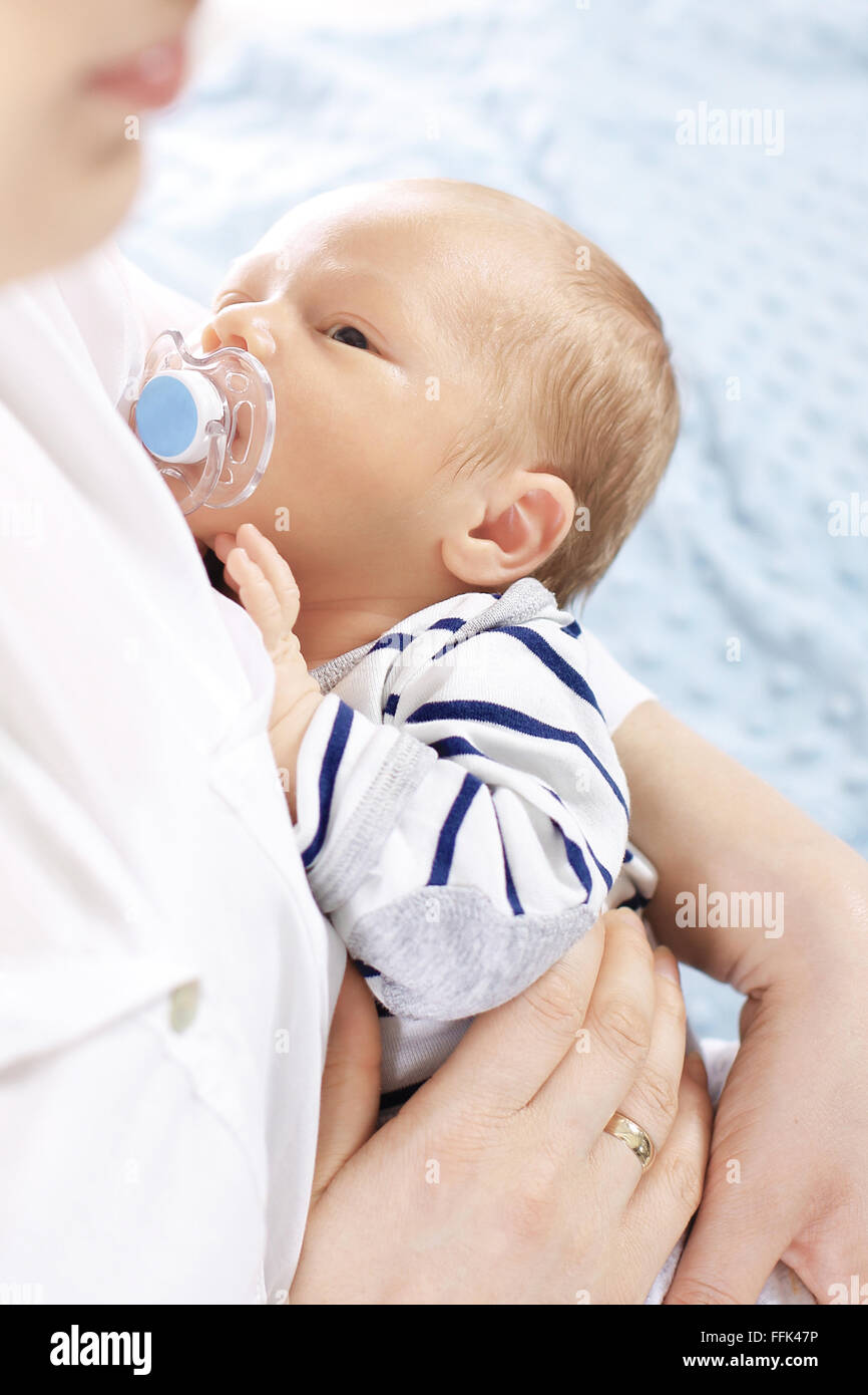 A woman holds in her arms her newborn baby . Little man, baby clinging ...