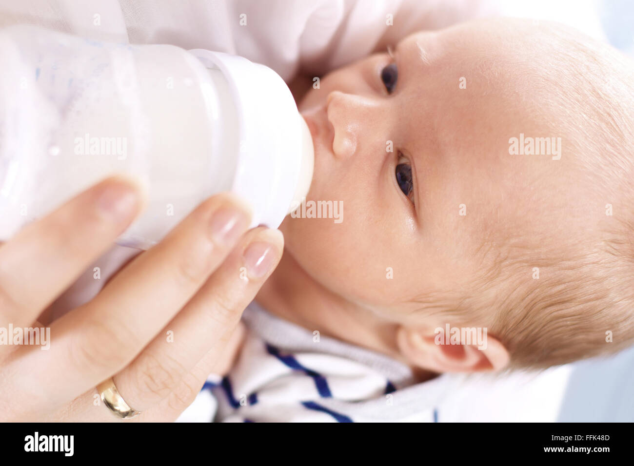 Bottle-fed baby. A woman feeds a newborn with modified milk from a ...