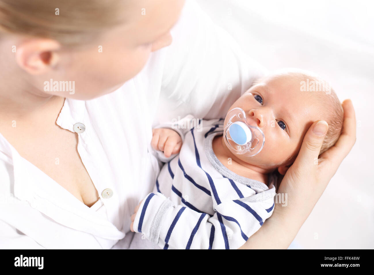 A woman holds in her arms her newborn baby . Little man, baby clinging ...