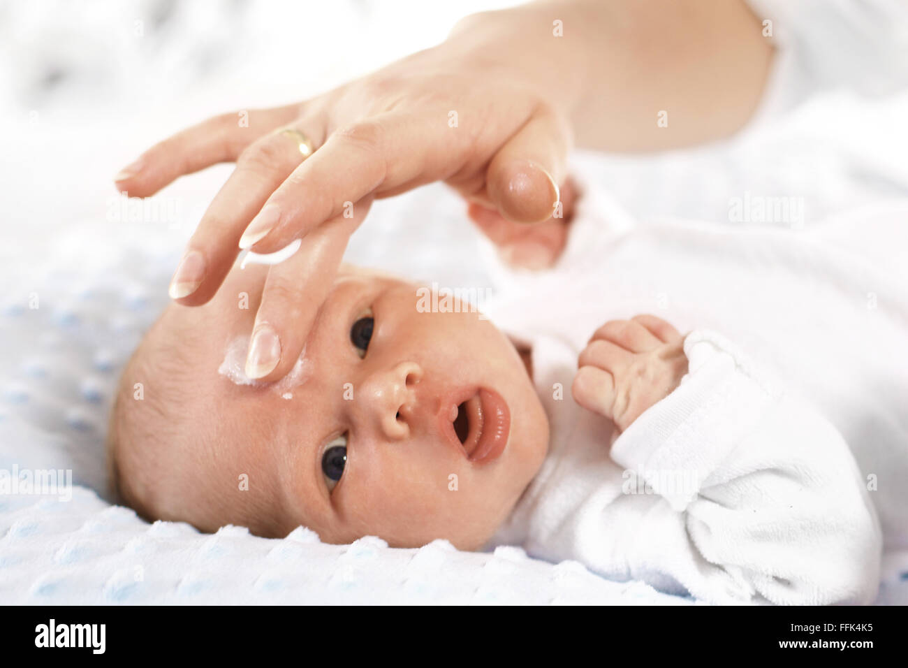 Mother lubricates the newborn face protective cream. Skin Care newborn ...