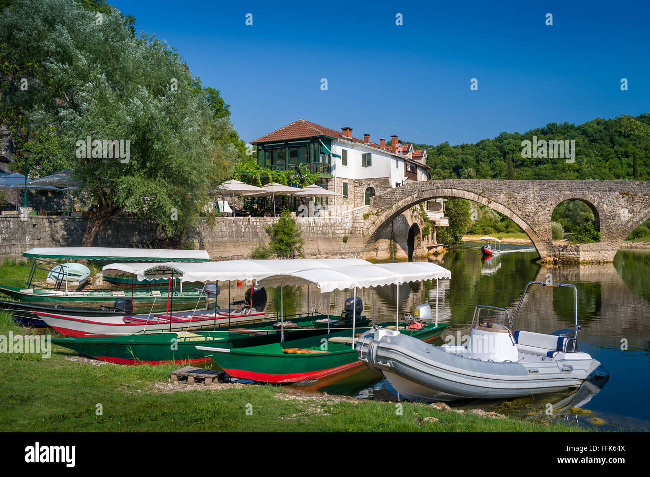 Rijeka Crnojevica old town excursion boats moored. Ancient arch bridge at background Stock Photo ...