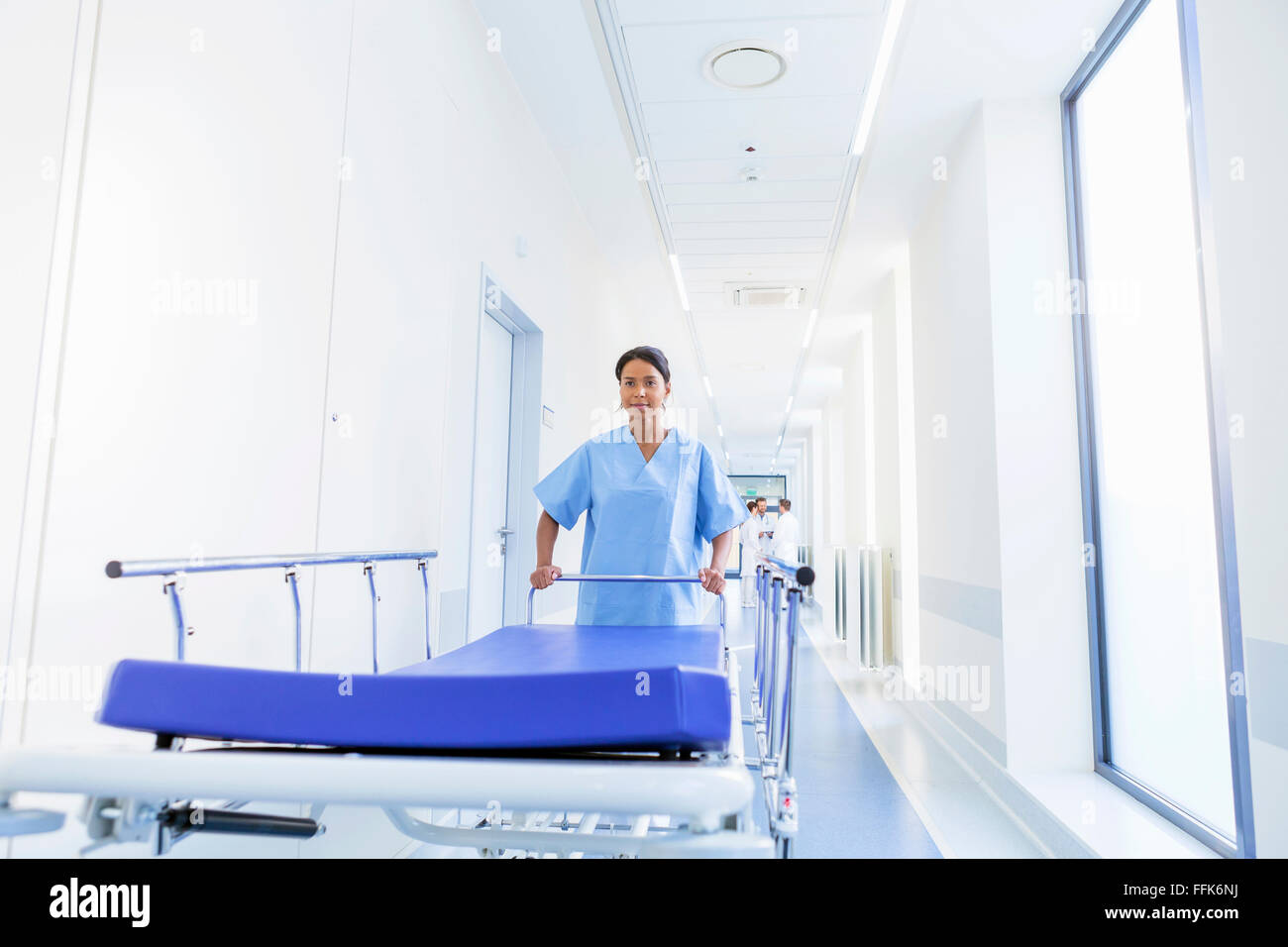 Healthcare worker pushing hospital gurney in corridor Stock Photo - Alamy