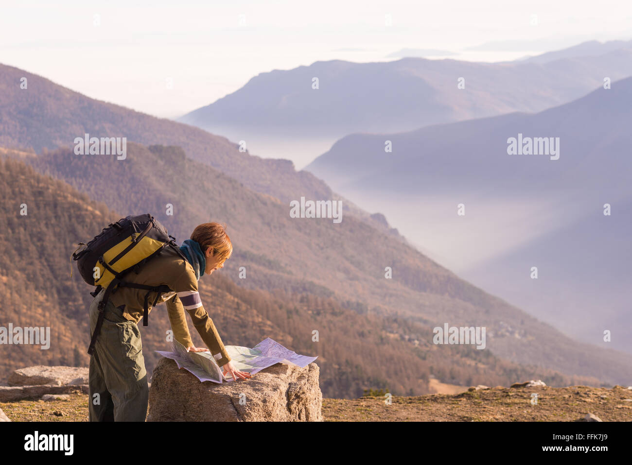 Female hiker with backpack reading trekking map while resting at ...