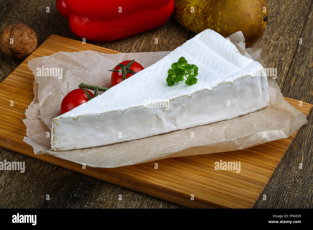 Brie cheese triangle with tomato and parsley Stock Photo - Alamy
