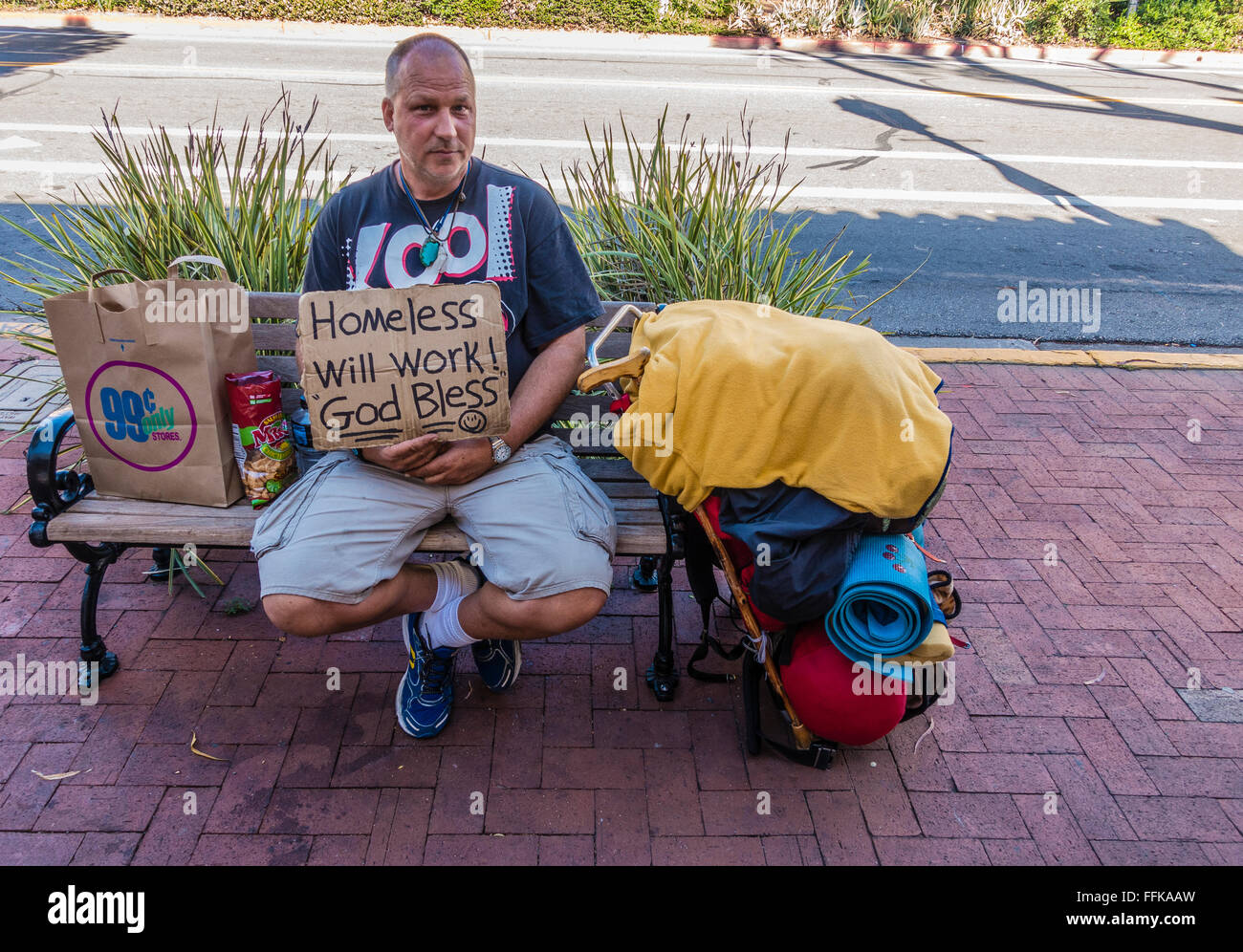 A middle-aged male beggar sits on a public bench on a State Street ...