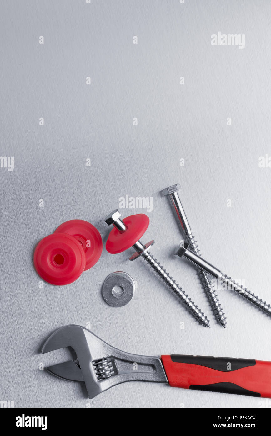 Spanner tool and screws on metal finish background Stock Photo - Alamy