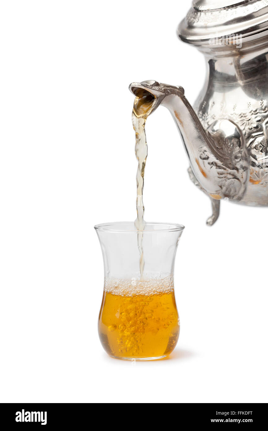 Traditional Moroccan mint tea poured in a glass on white background ...