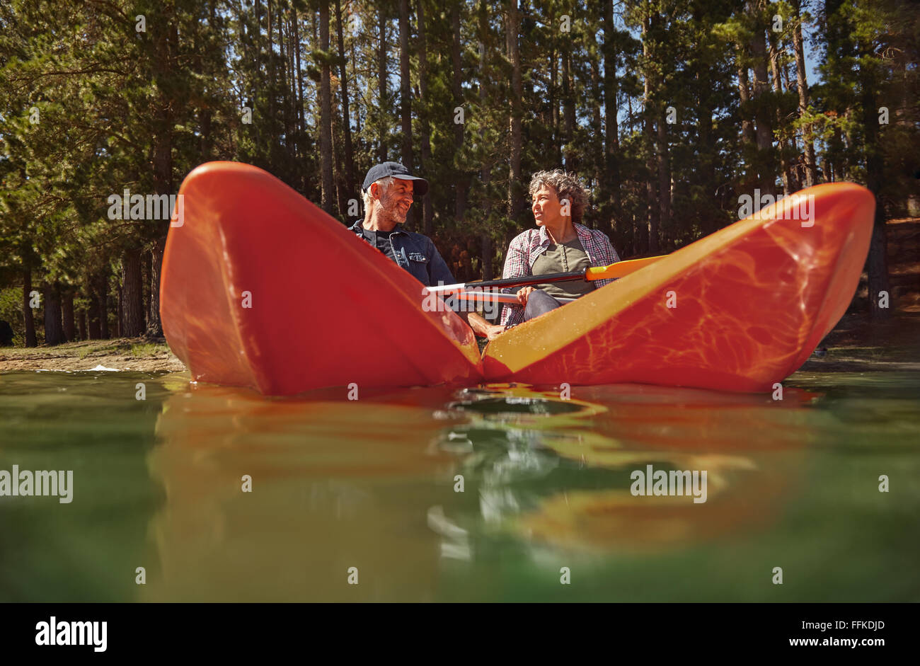 Active senior couple in two single kayaks side by side. Mature man and ...