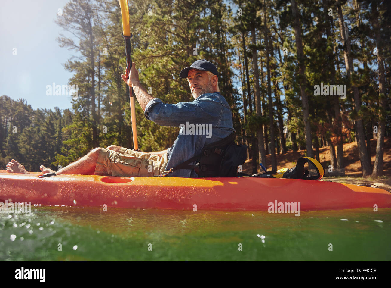Portrait of a senior man with kayak in a lake. Caucasian man paddling a ...