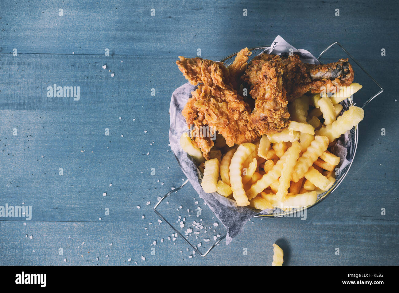 Chicken fries strips and legs with French fries in metal basket over ...