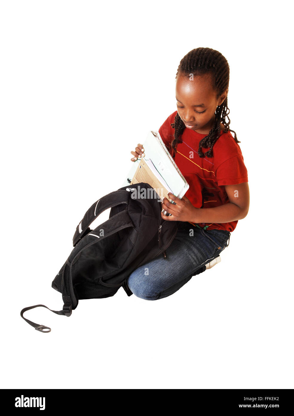 A young black school girl looking into her school backpack, kneeling on ...
