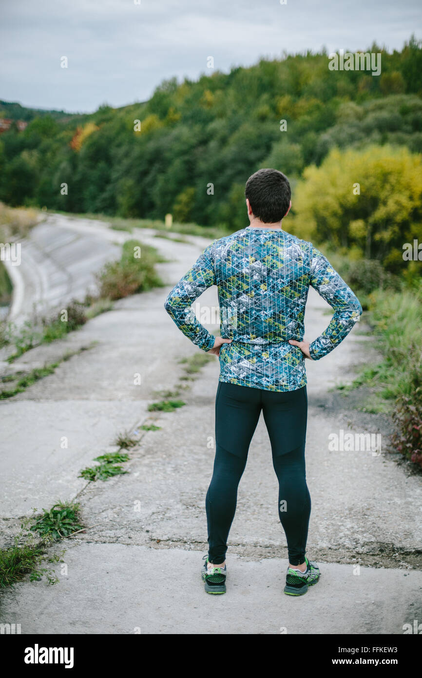 Runner resting, path in green nature, back view Stock Photo - Alamy