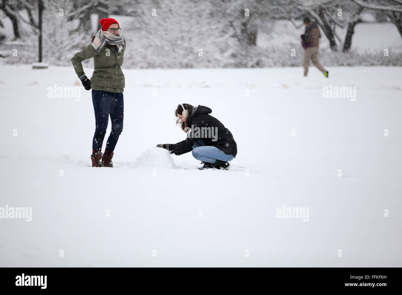 Two young women make a small mound of snow Stock Photo - Alamy