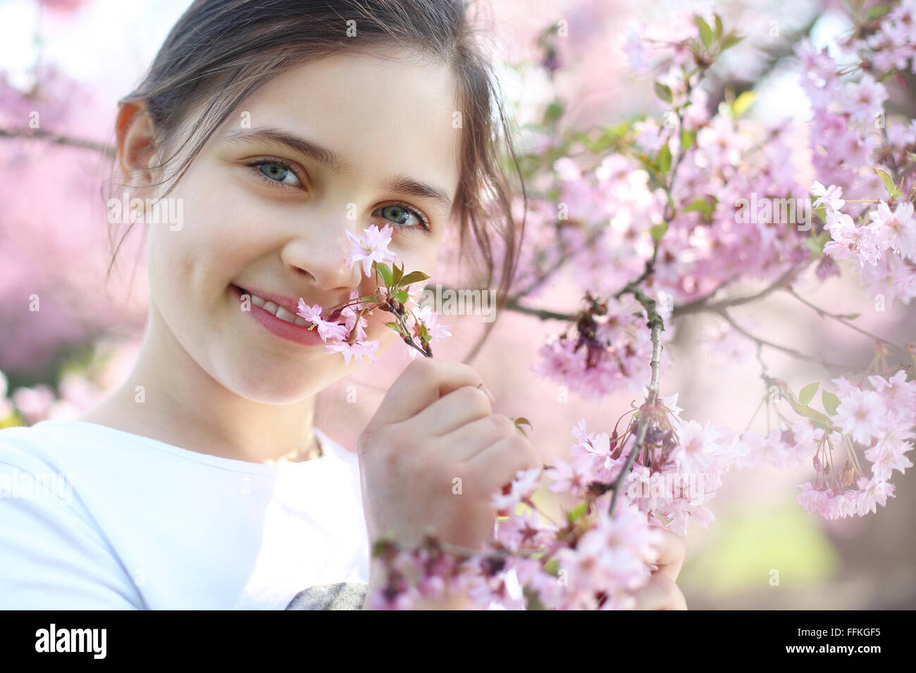 Beautiful little girl smelling flowers growing fruit trees in the ...