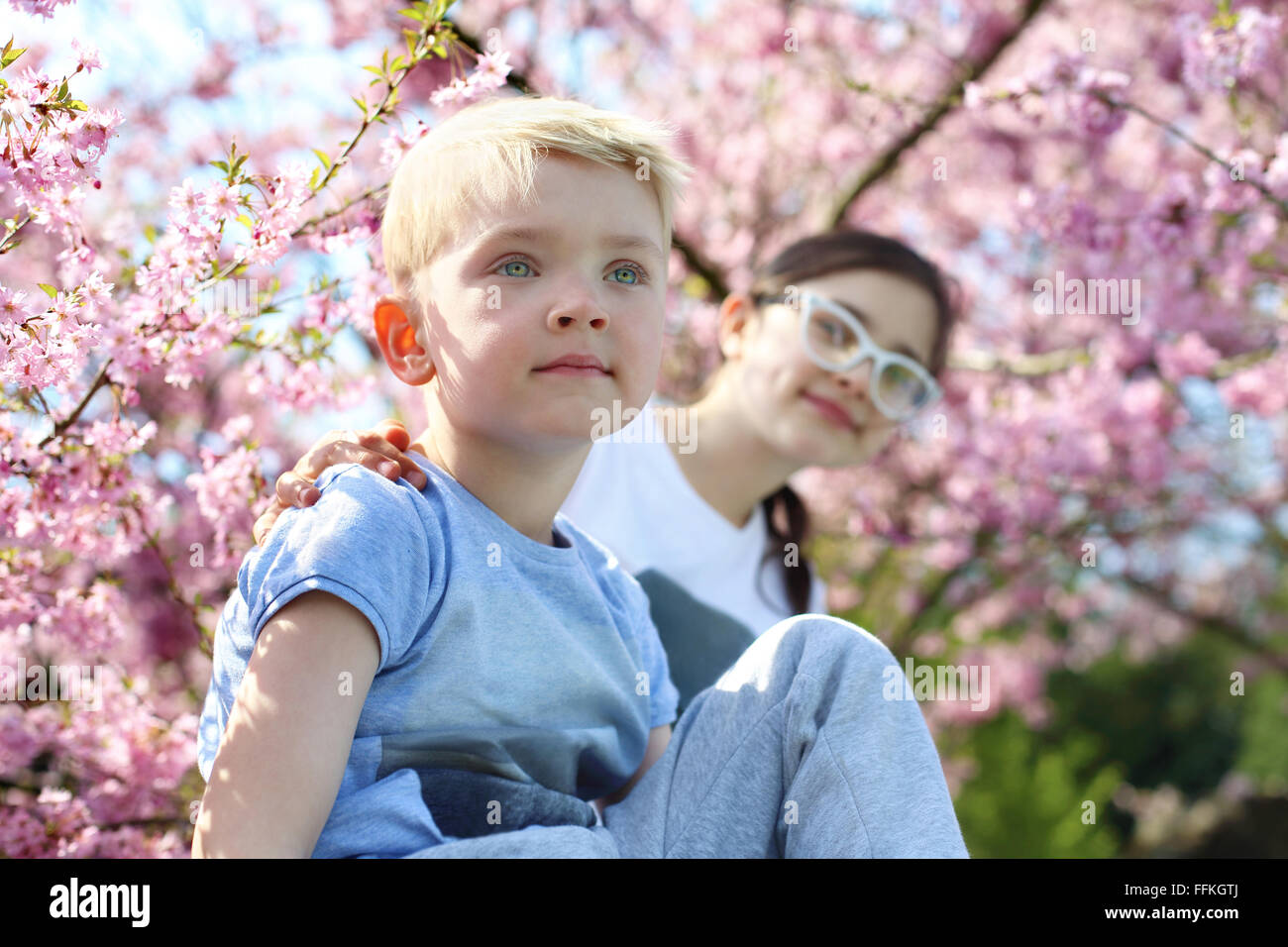 Siblings. Happy child. Boy sitting under a tree, the girl in the ...