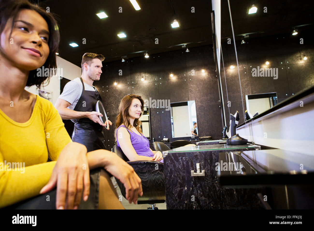 Customer with hairstylists in hair salon Stock Photo - Alamy