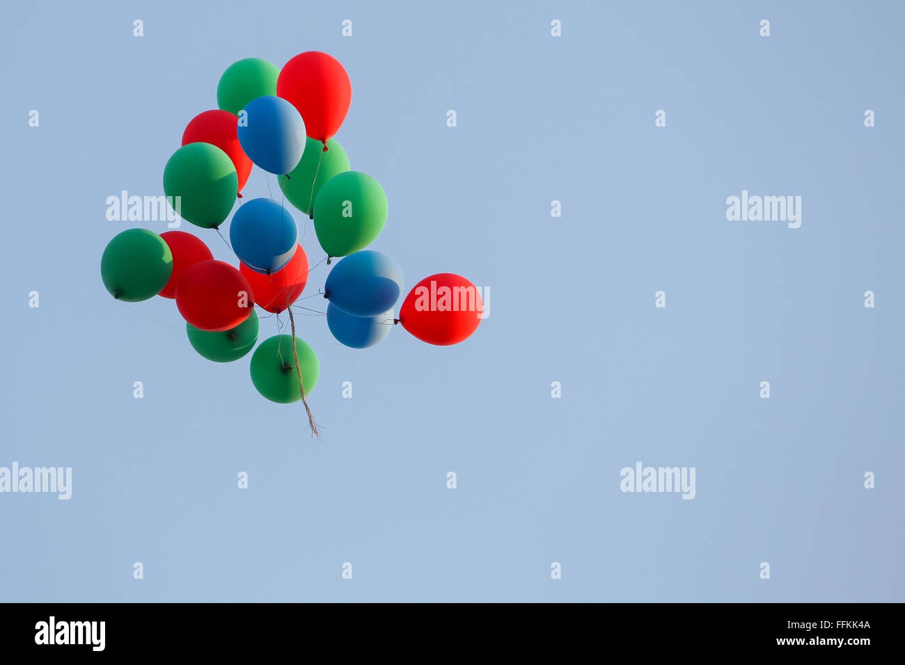 A view from below of a group of colorful balloons flying in the air ...