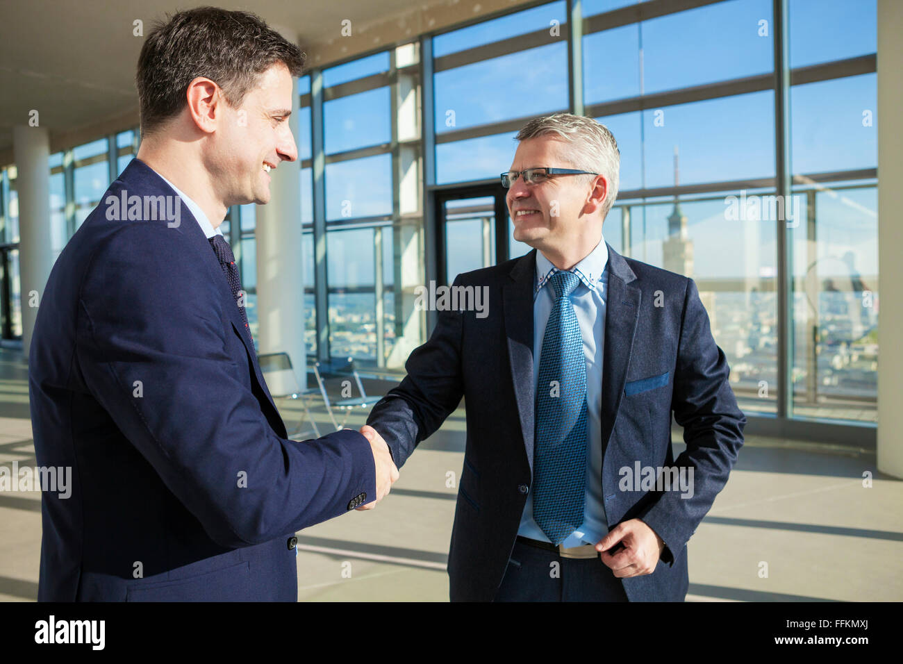 Two businessmen shaking hands in modern office Stock Photo - Alamy