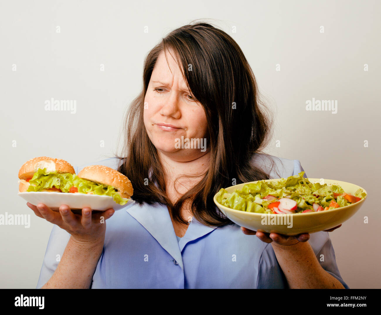fat white woman having choice between hamburger and salad close up ...