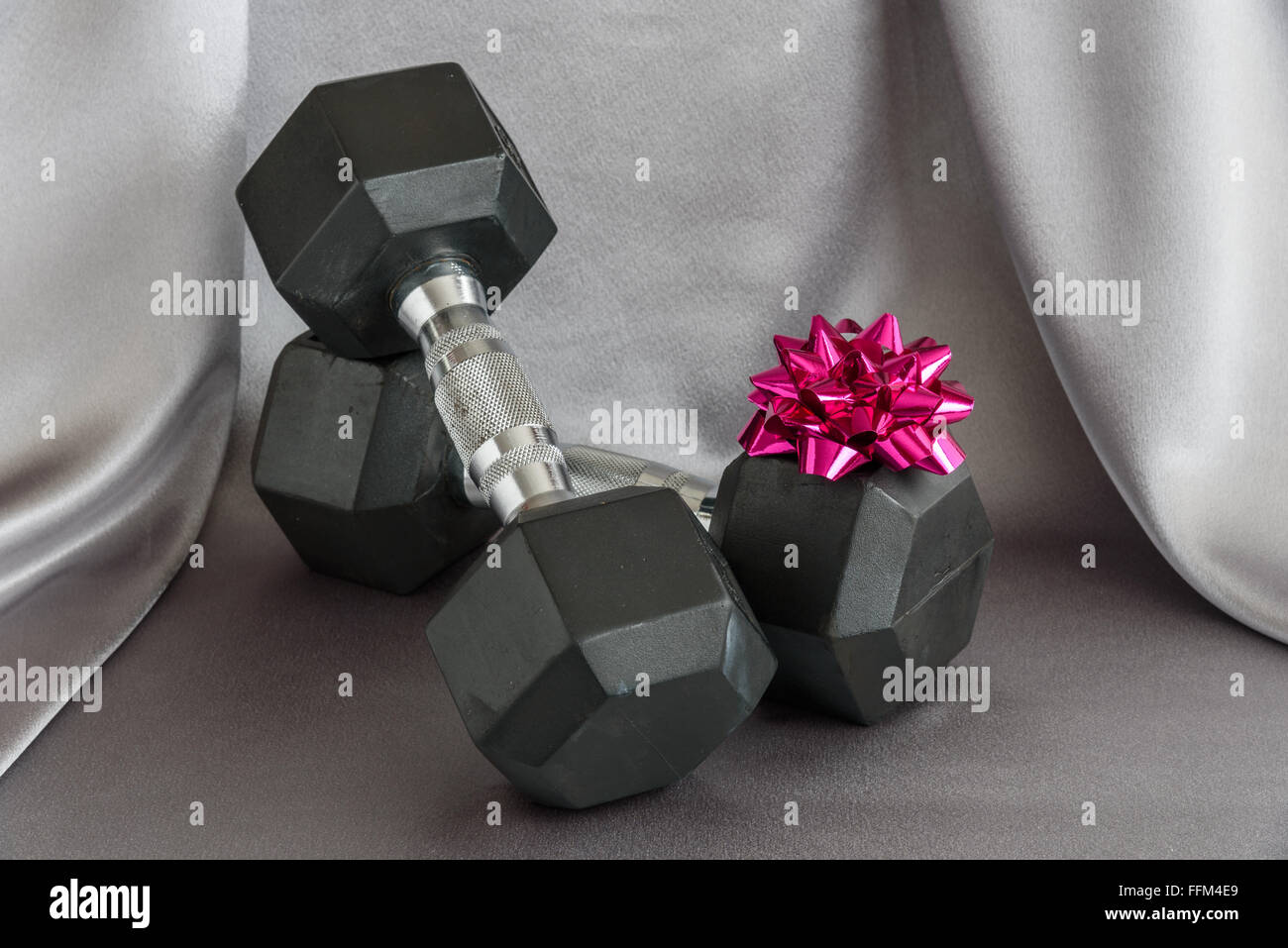 Set of black and silver dumbbells with a pink bow on a silver ...