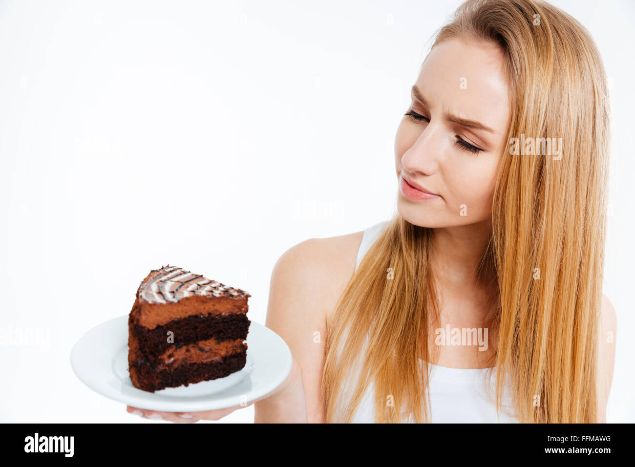 Pensive beautiful young woman looking at piece of chocolate cake over ...