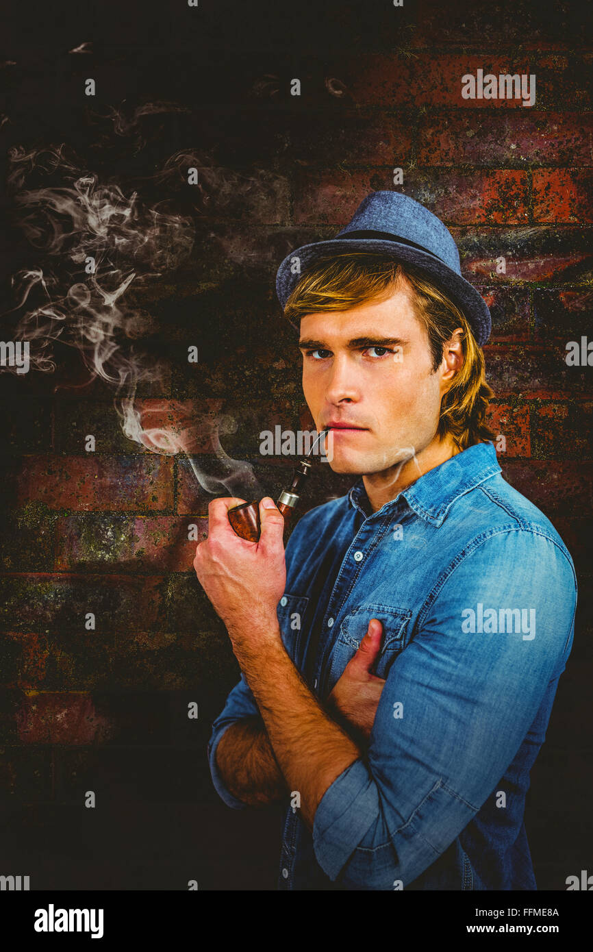 Composite image of serious hipster smoking pipe Stock Photo - Alamy