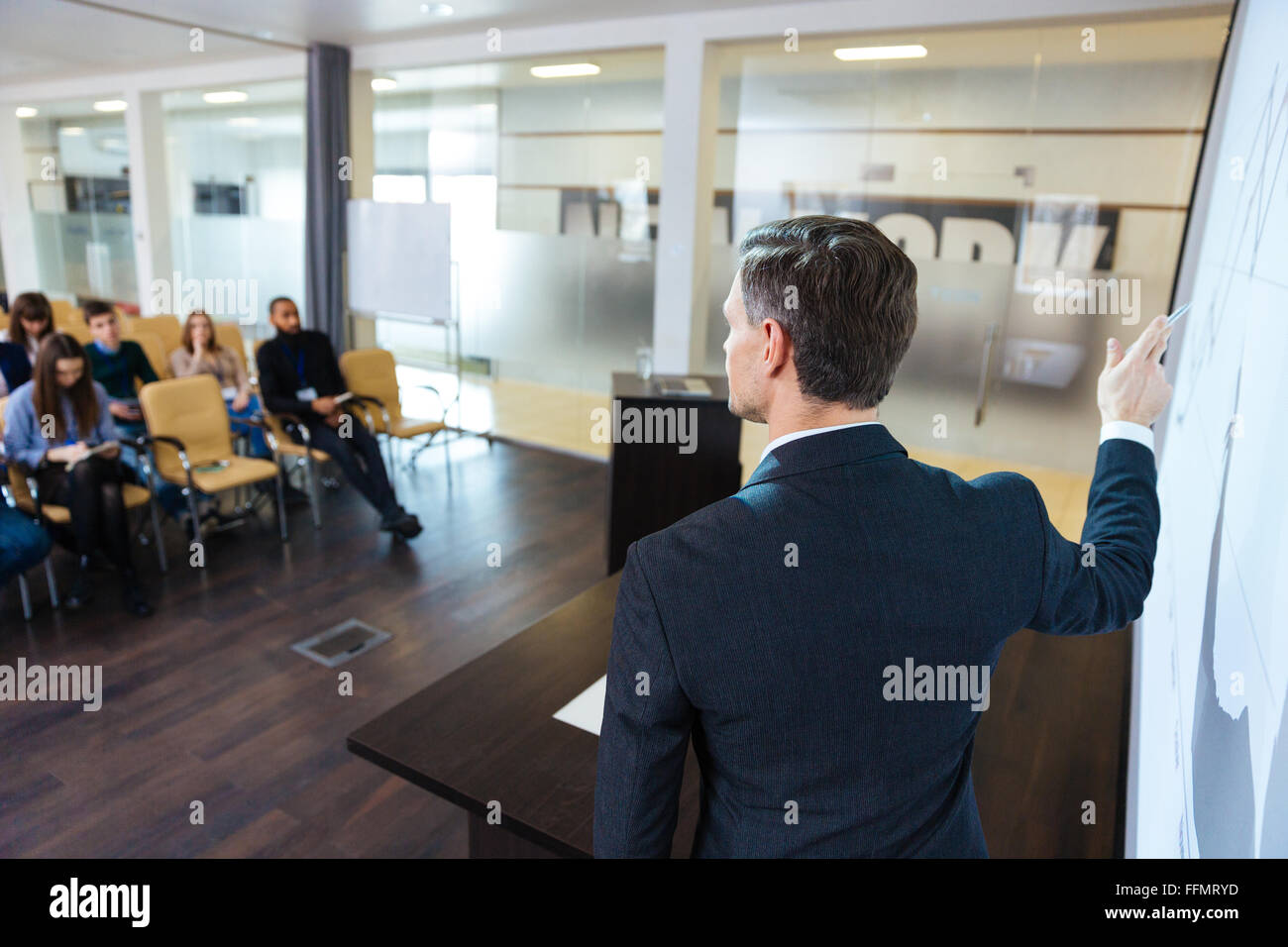Back view of intelligent speaker on business conference in meeting hall ...