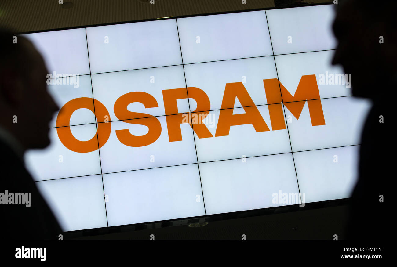 Munich, Germany. 16th Feb, 2016. Two men talk with a screen featuring ...