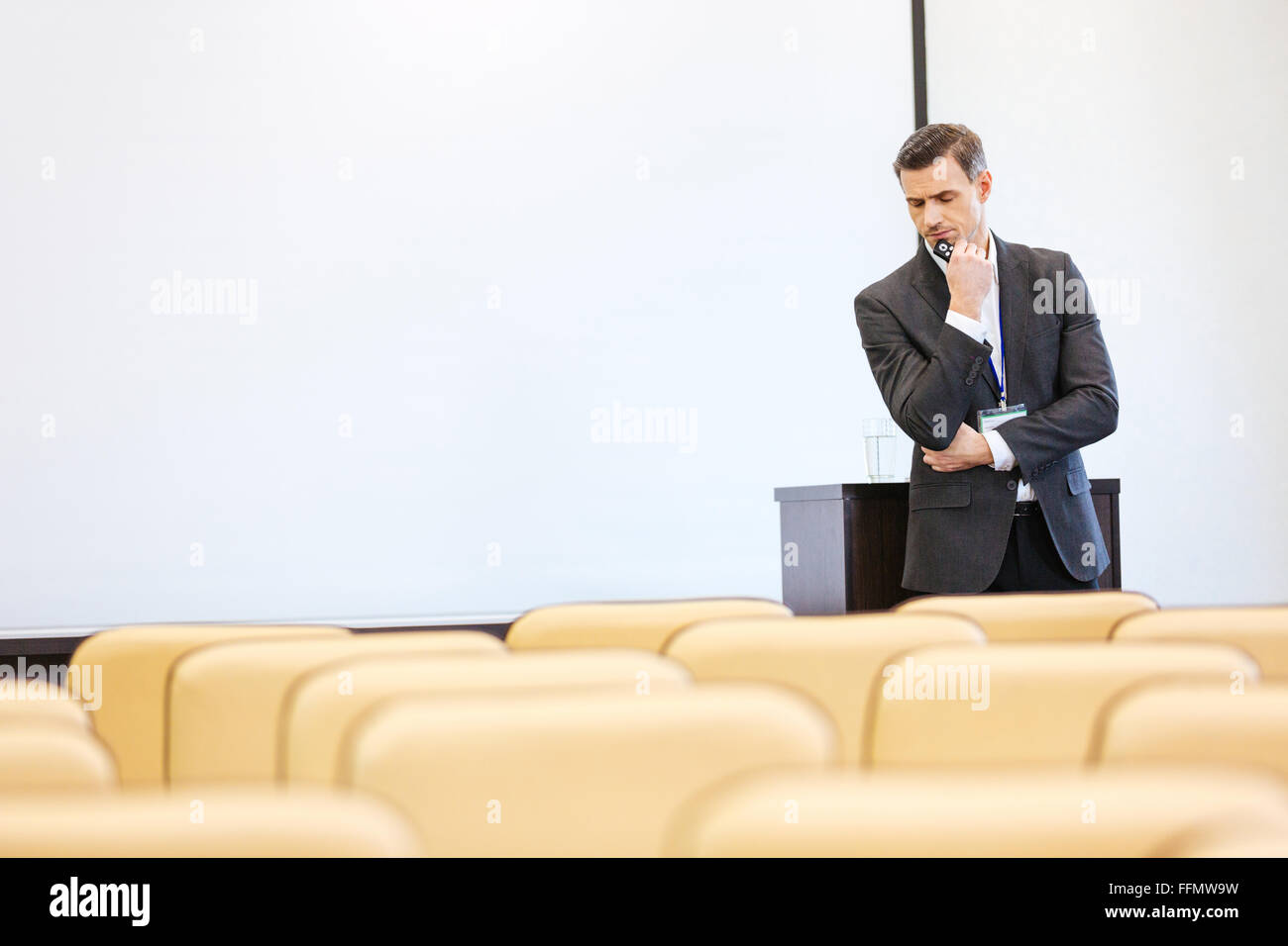 Thoughtful serious businessman standing and thinking in empty ...