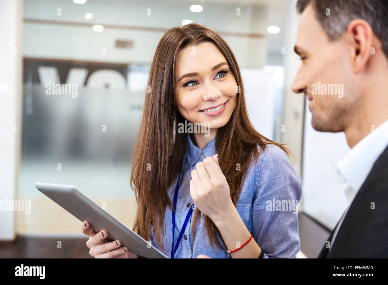 Happy pretty young business woman talking to her client and using ...